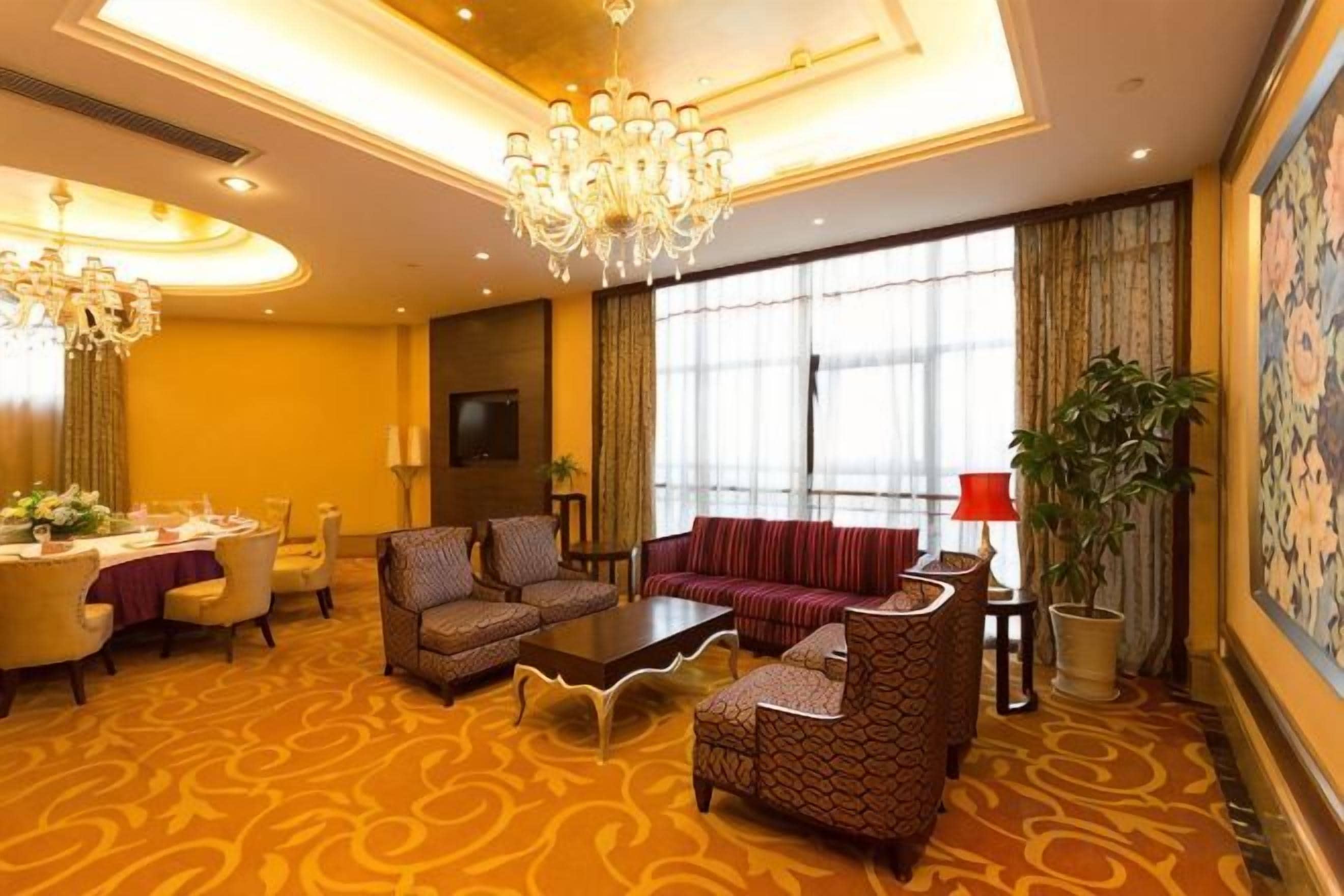 Quarto de hotel com sofá, mesa de jantar e lustre.