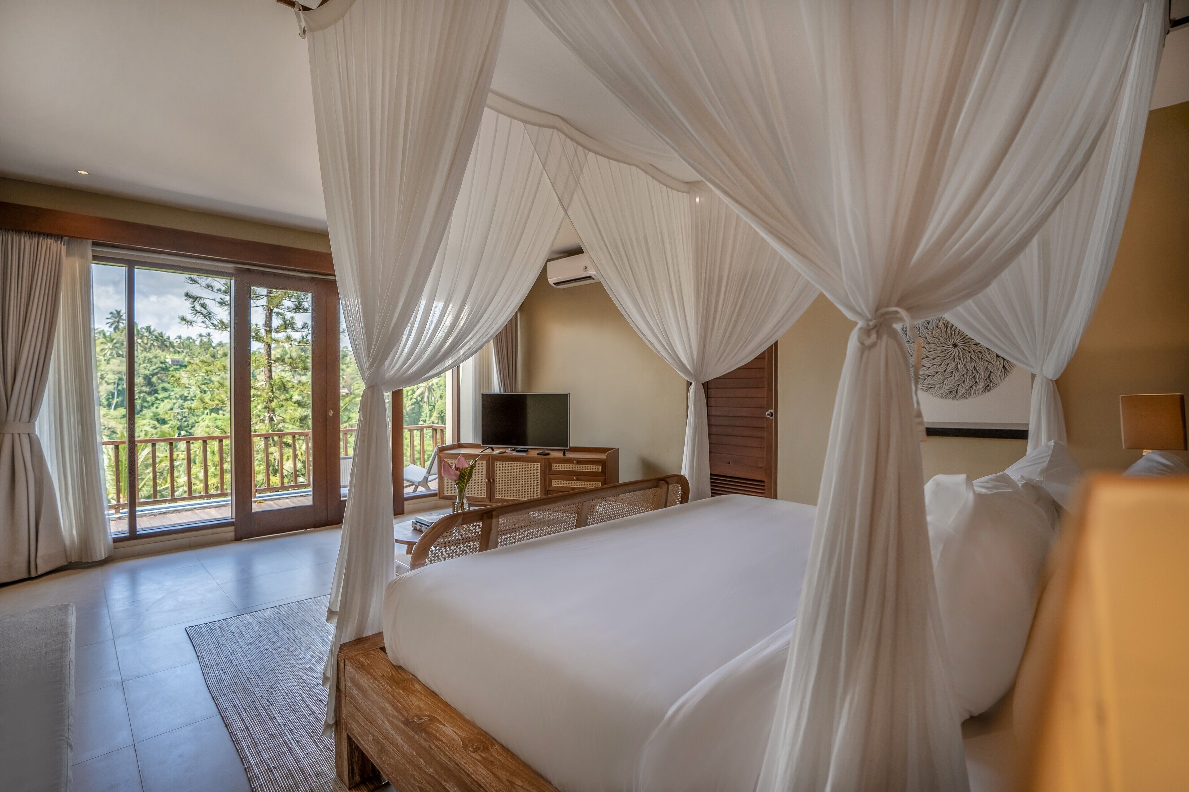 Quarto com cama de dossel, televisão e mesa de cabeceira de madeira.