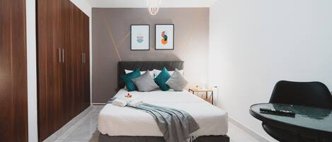 Quarto moderno com cama, mesa de cabeceira e um espaço de refeições com mesa e cadeiras.