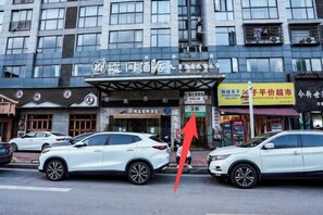 Entrada de hotel com placa indicando classificação de 3 estrelas, uma seta vermelha apontando para a entrada e fachada de edifício com várias janelas e sacadas.