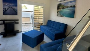 Uma sala de estar moderna com um sofá azul, uma mesa pequena e uma escada.