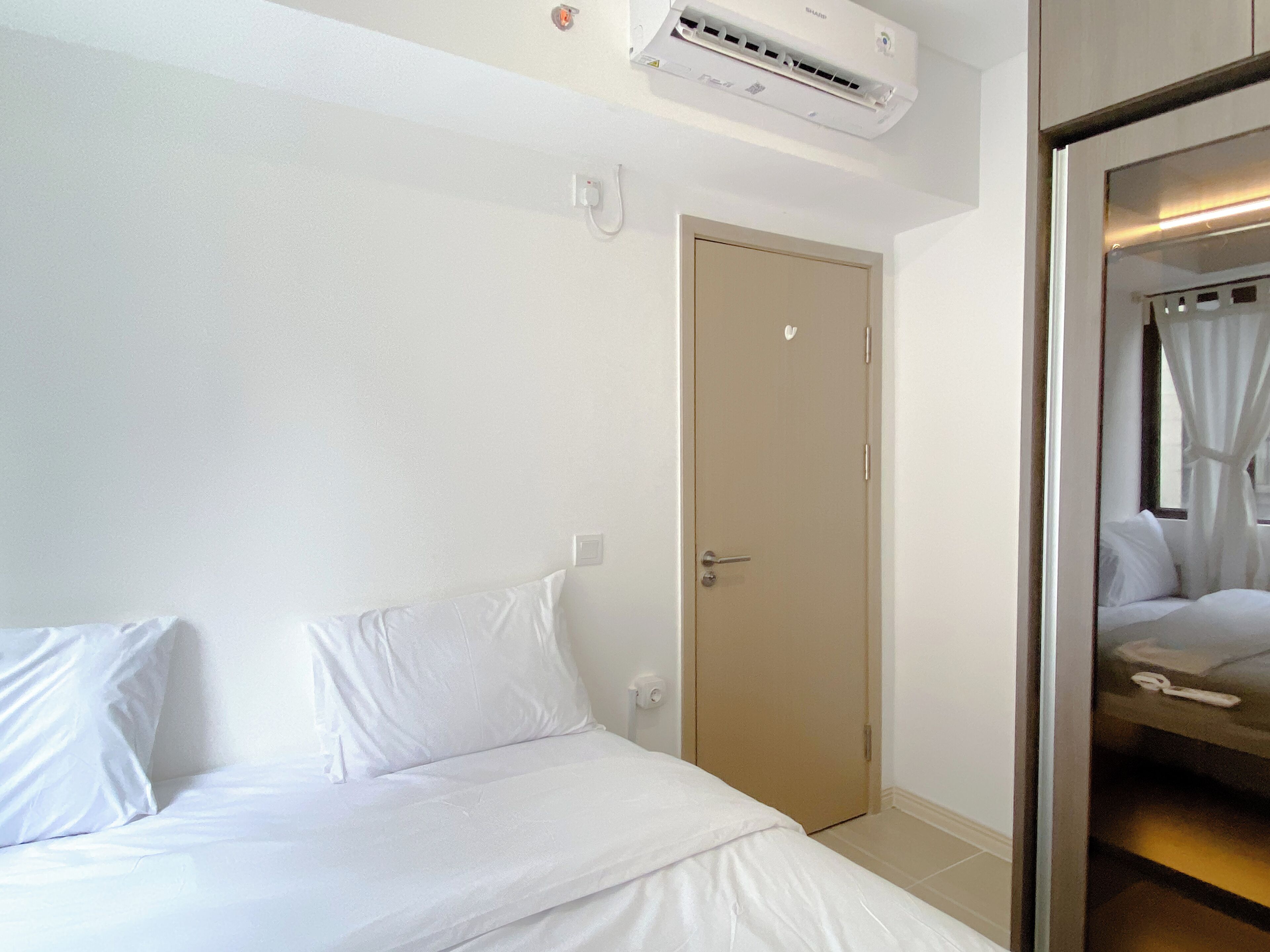 Quarto de hotel com cama, porta e unidade de ar condicionado na parede.