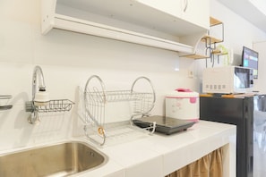 Uma cozinha moderna com uma pia de aço inoxidável, um escorredor de louça, um micro-ondas e uma cafeteira.