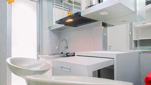 Cozinha moderna com armários brancos, forno embutido e coifa de aço inoxidável.