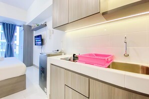 Quarto de hotel moderno com cozinha compacta, cama, televisão e vista para a cidade.