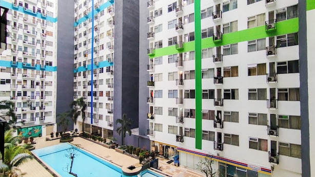 Um edifício residencial alto com várias varandas, uma piscina e uma pequena área de jardim.