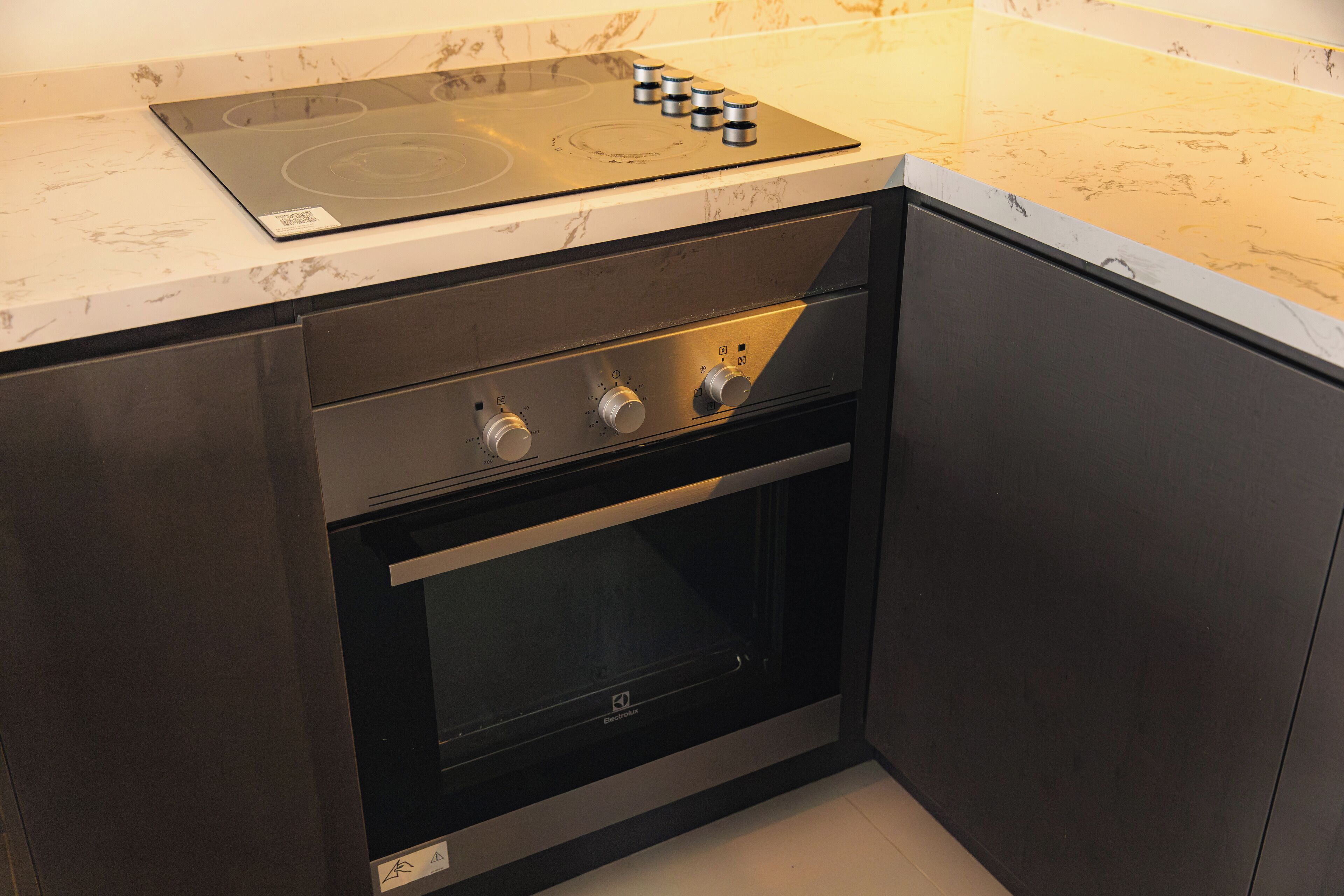 Cozinha equipada com fogão por indução embutido, micro-ondas e forno de aço inoxidável.