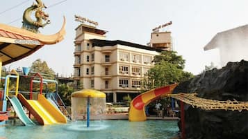 Um parque aquático com toboáguas e piscina, cercado por edifícios com sacadas.