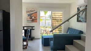 Um espaço de estar moderno com uma escada que leva a uma varanda, uma área de refeições e uma cozinha.