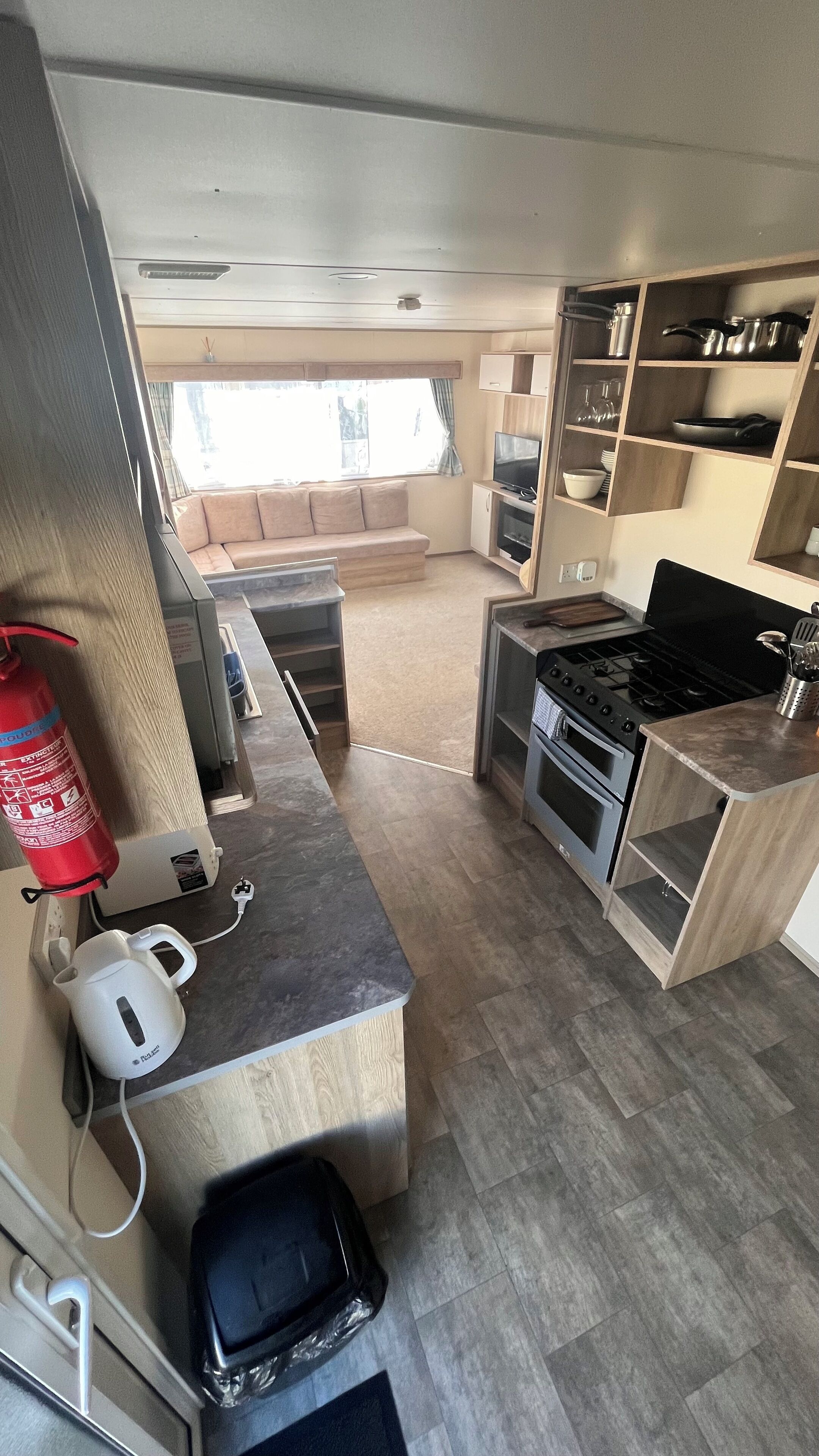 Uma cozinha compacta com fogão, forno e uma pequena área de refeições com sofá.