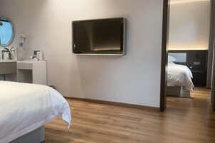 Quarto de hotel moderno com cama, escrivaninha, espelho e televisão de tela plana na parede.