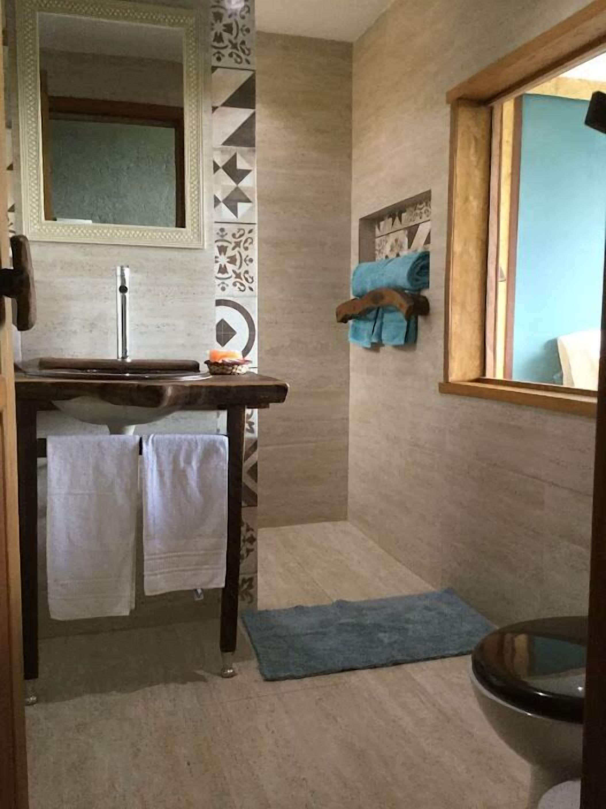 Casa de banho com lavatório, espelho e porta-toalhas.