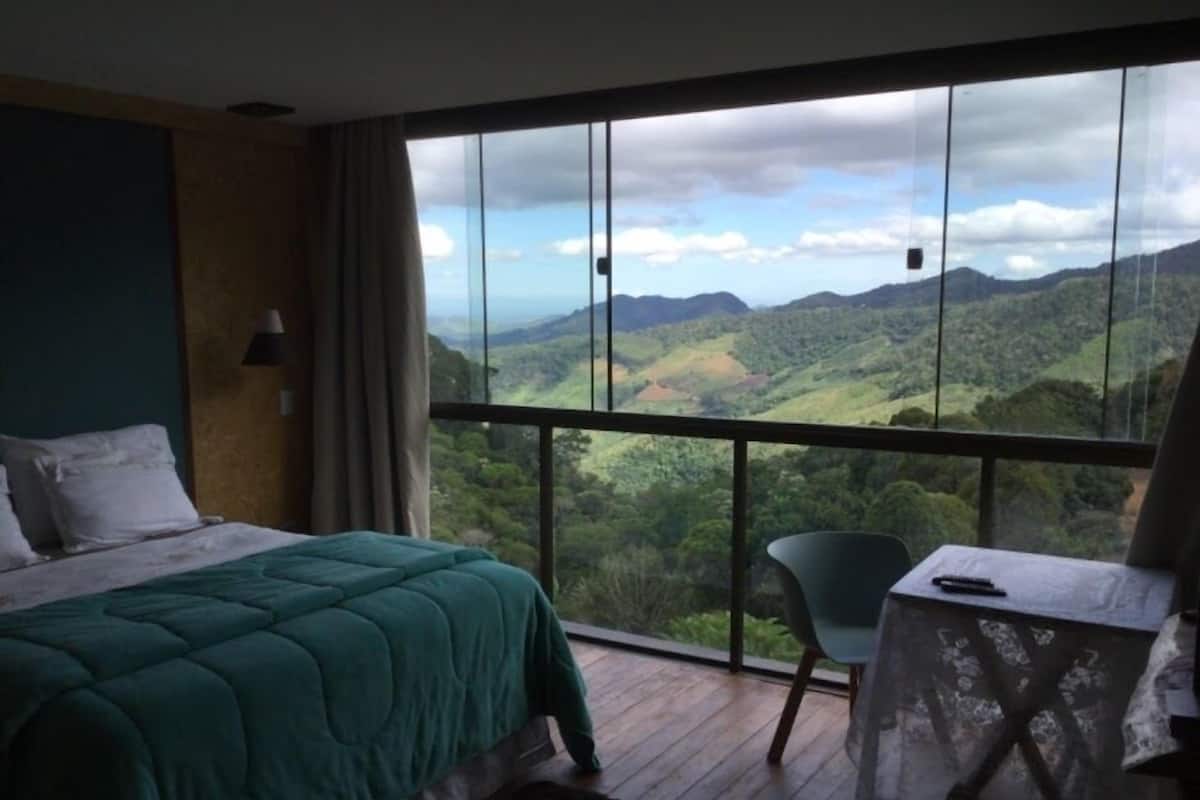 Quarto com uma janela grande com vista para as montanhas.