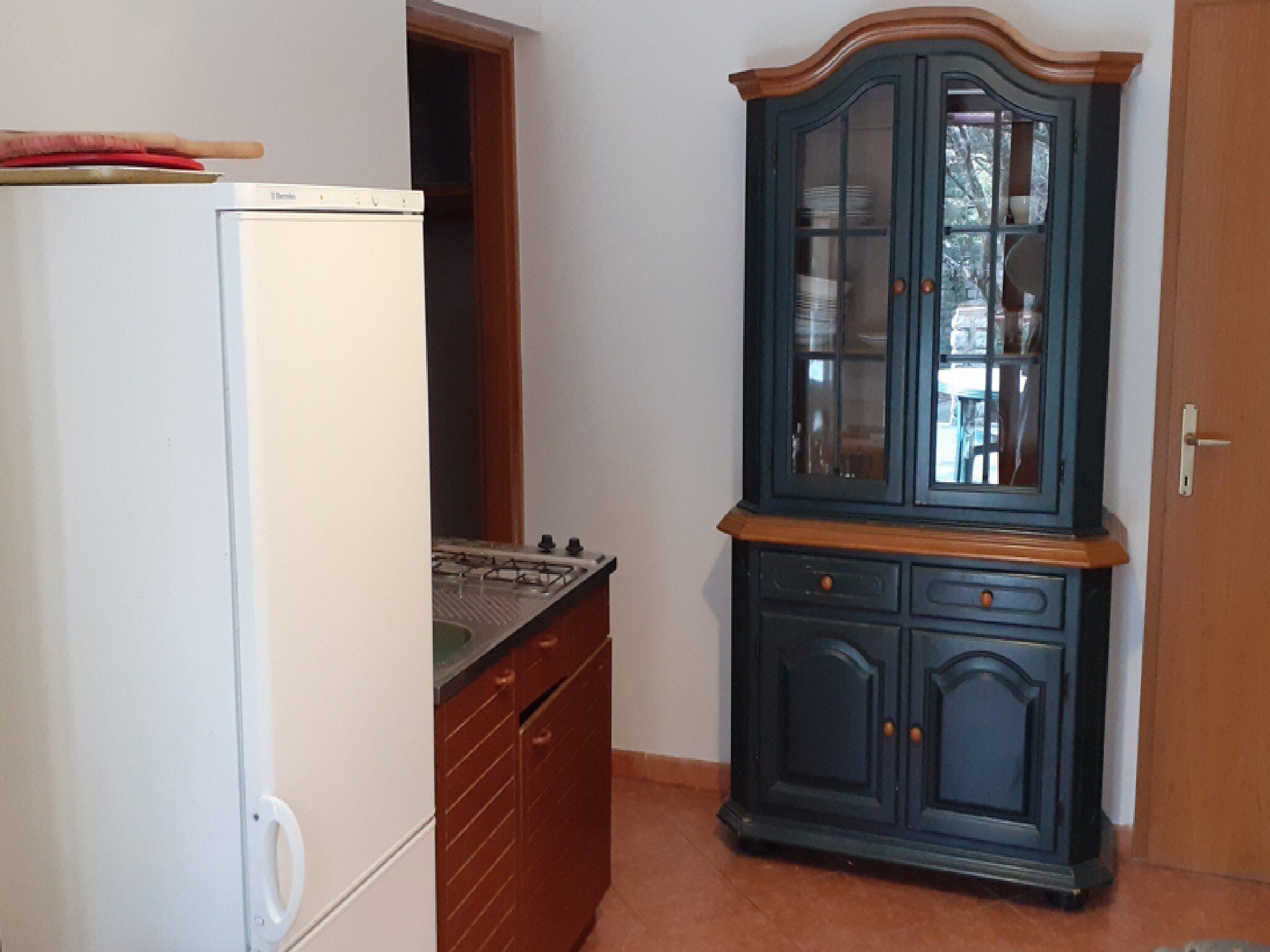 Uma cozinha com geladeira branca, fogão e armário de madeira com portas de vidro.