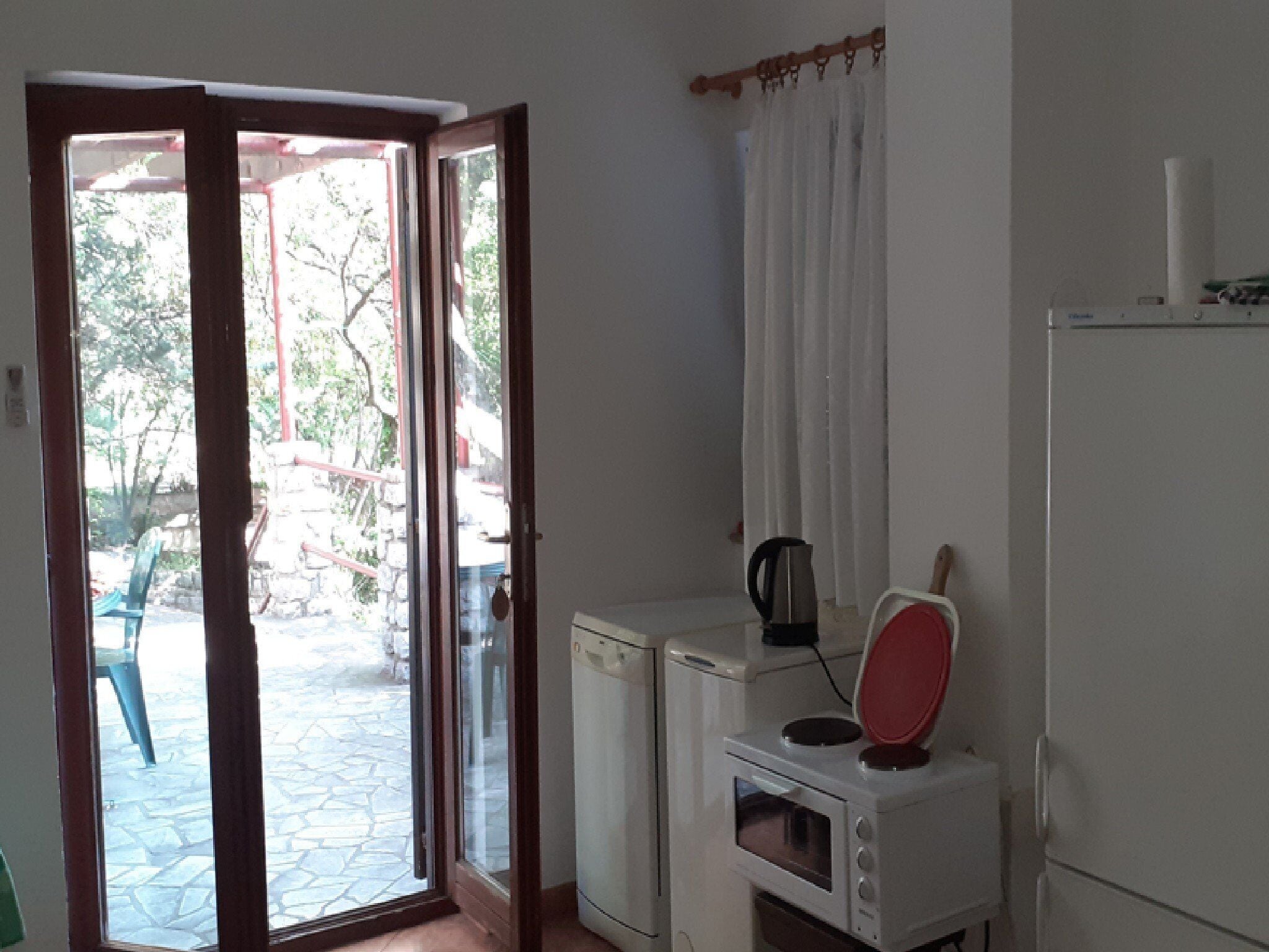 Cozinha compacta com geladeira, micro-ondas, chaleira e pia pequena.