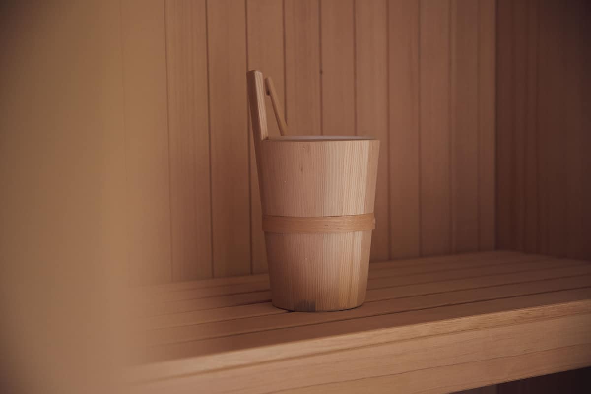 Uma caneca de madeira com alça sobre uma prateleira, em frente a uma parede de madeira.