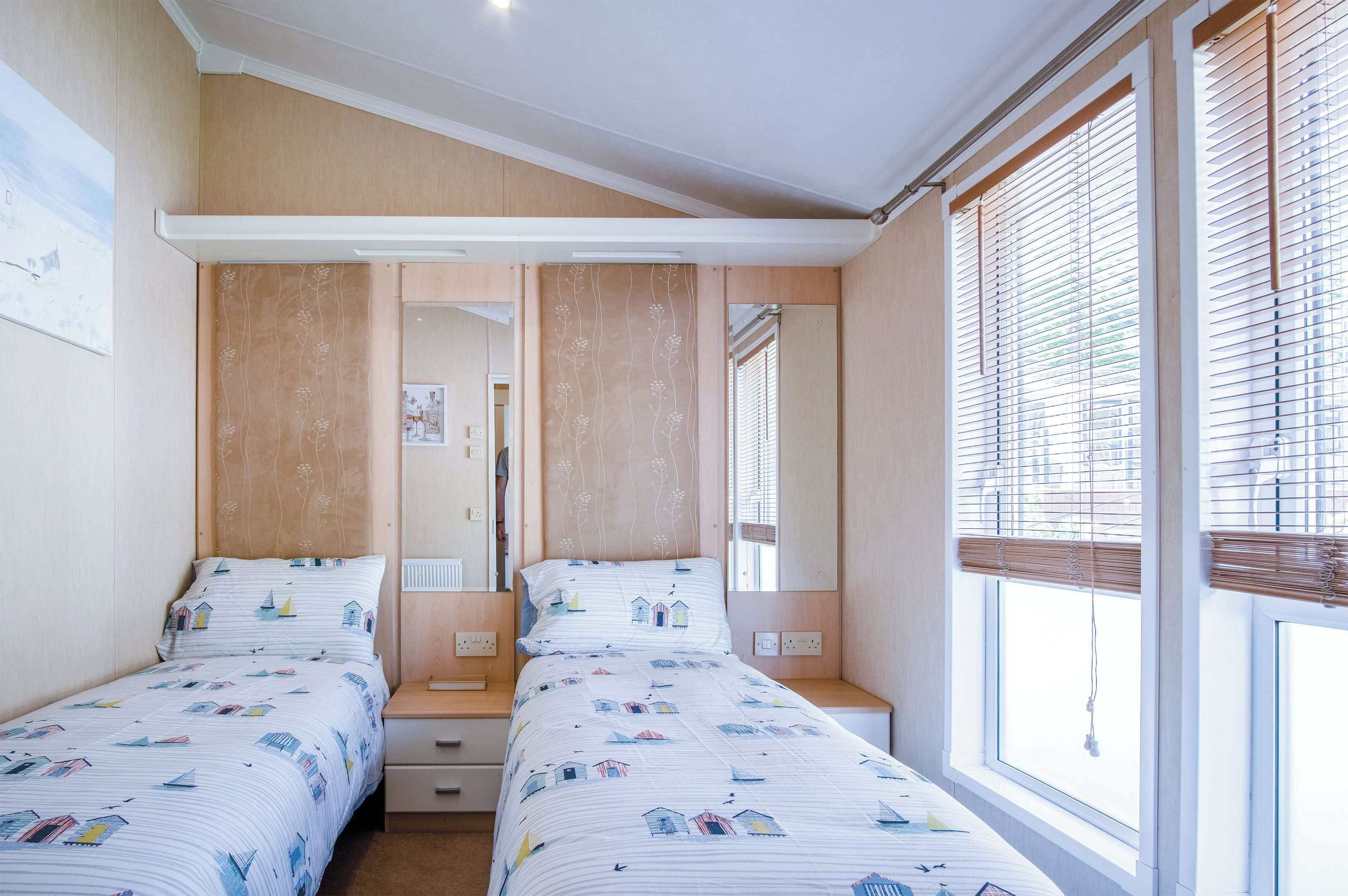 Quarto com duas camas, um guarda-roupa e uma janela com persianas.