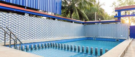 Piscina com azulejos estampados em azul e branco, rodeada por uma estrutura azul e vermelha.