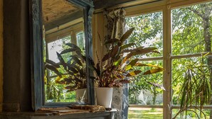 Um quarto com piso xadrez, lareira, um espelho grande e plantas em vasos.