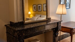 Um aparador de mármore com um espelho refletindo uma cama e um abajur.