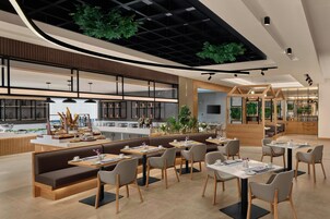 Um restaurante moderno com teto curvo, assentos de madeira e uma área de cozinha visível ao fundo.