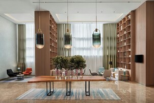 Um interior moderno com um balcão de recepção de madeira, luminárias pendentes e uma estante grande.
