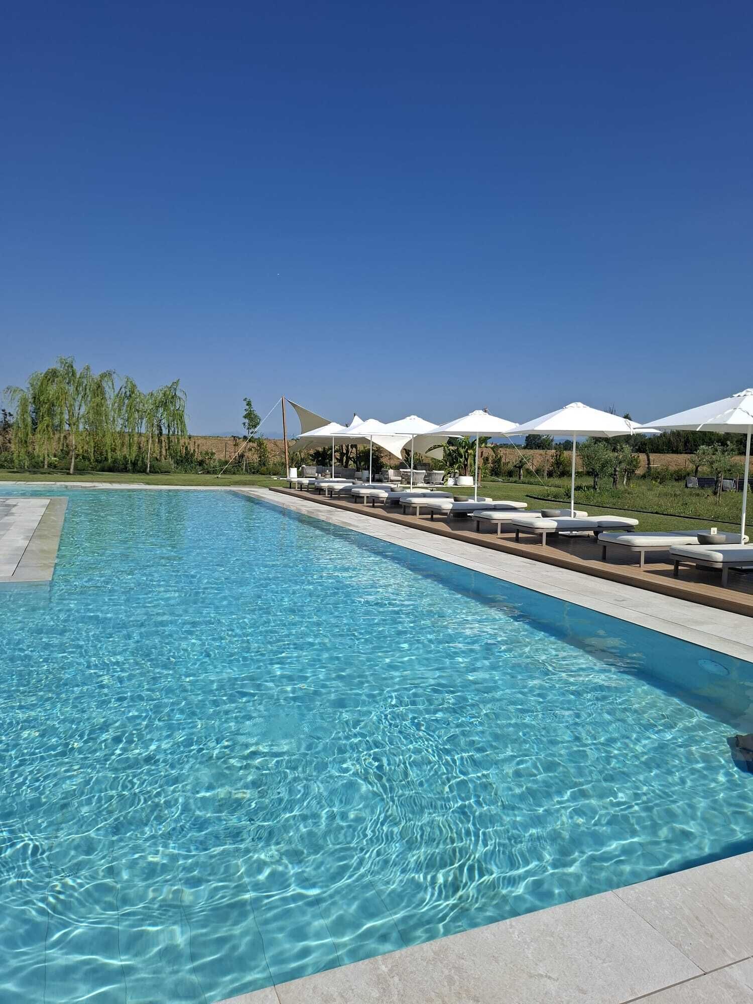 Piscina azul clara com espreguiçadeiras e guarda-sóis.