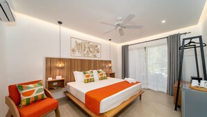 Quarto de hotel moderno com uma cama grande, uma cadeira de madeira, uma escrivaninha e um ventilador de teto.