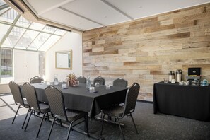 Uma sala de conferências com uma mesa comprida, cadeiras, um espaço para café e uma grande janela.