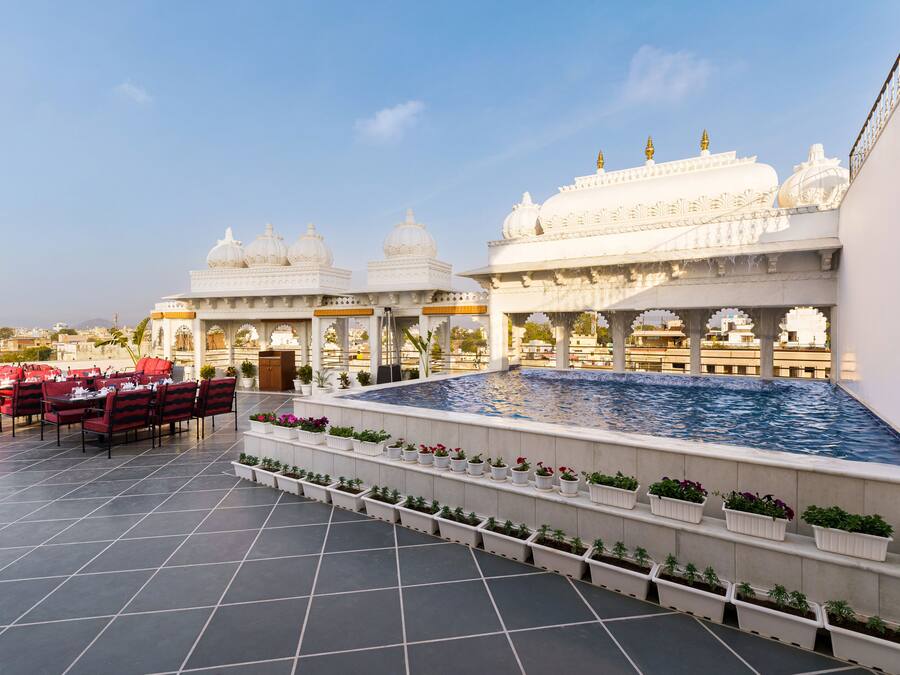 Terraço no telhado com piscina, área de refeições e arquitetura tradicional.