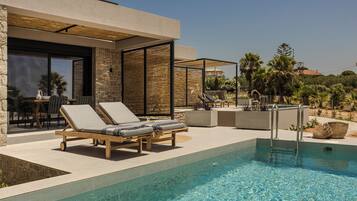 Uma área moderna de piscina ao ar livre, com espreguiçadeiras, piscina e um pátio com mobiliário externo.