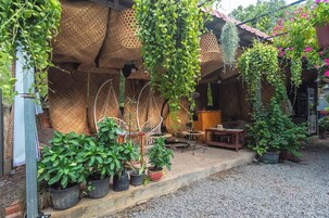 Uma área de estar rústica ao ar livre, com móveis de vime e plantas em vasos.