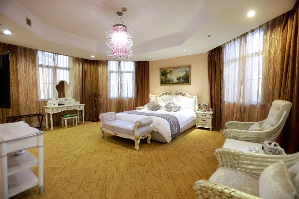 Um quarto espaçoso com uma cama grande, uma penteadeira, uma escrivaninha e uma cadeira.
