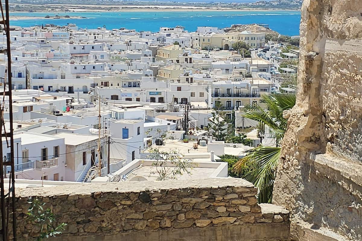 Uma vila costeira com edifícios brancos, uma parede de pedra e vista para o mar.