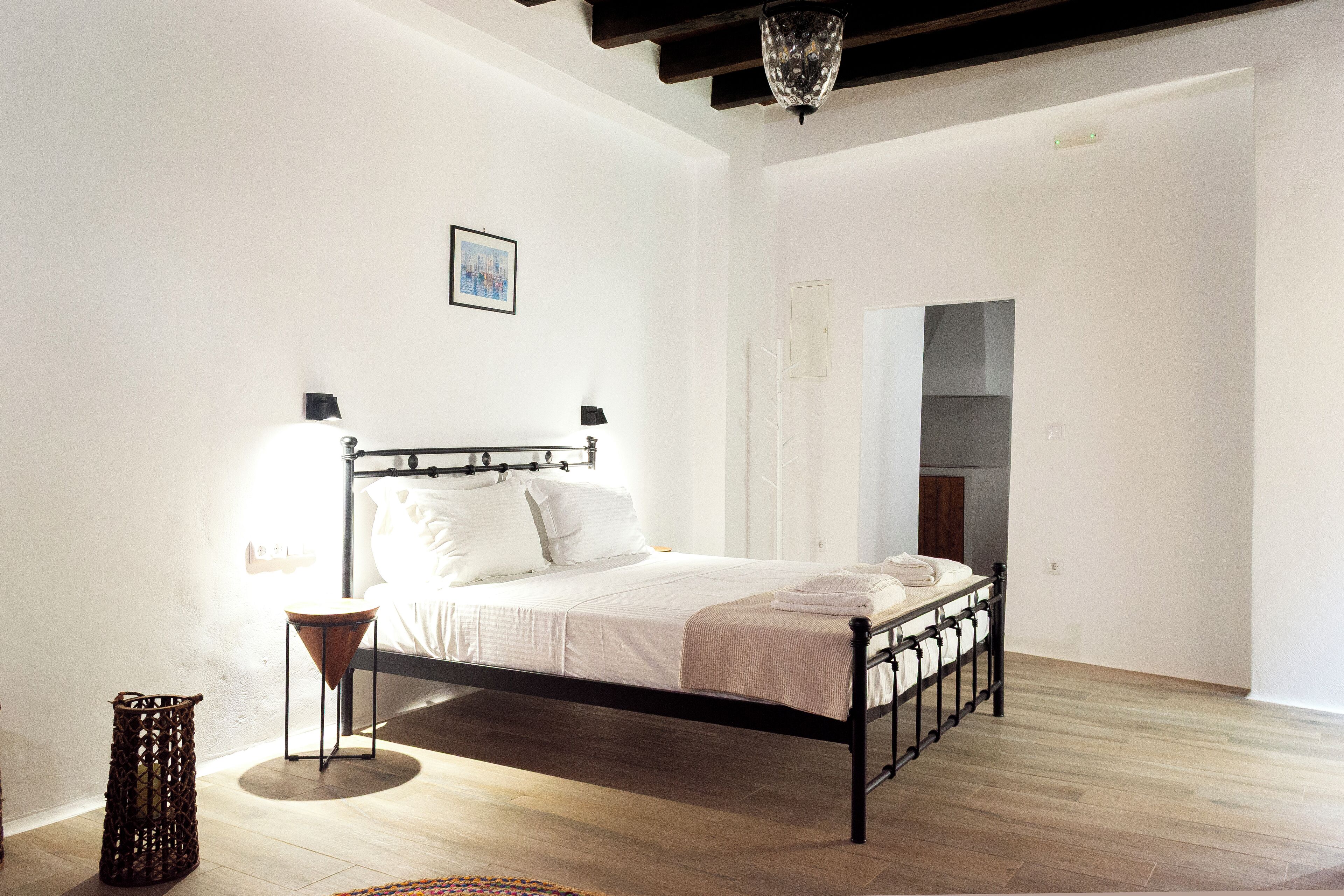 Quarto com cama, abajures, uma mesinha de cabeceira e luminária pendente.