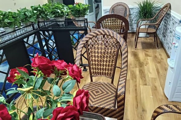 Quarto com piso de madeira, móveis de vime e plantas em vasos.