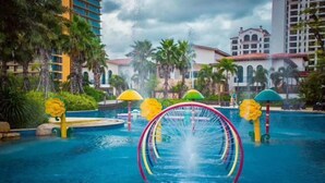 Piscina com características aquáticas coloridas e palmeiras.