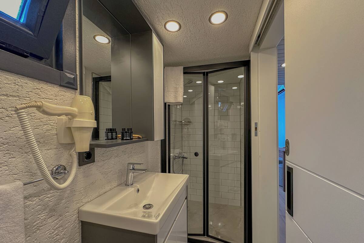 Uma casa de banho moderna com uma sanita branca, secador de cabelo e cabine de duche em vidro.