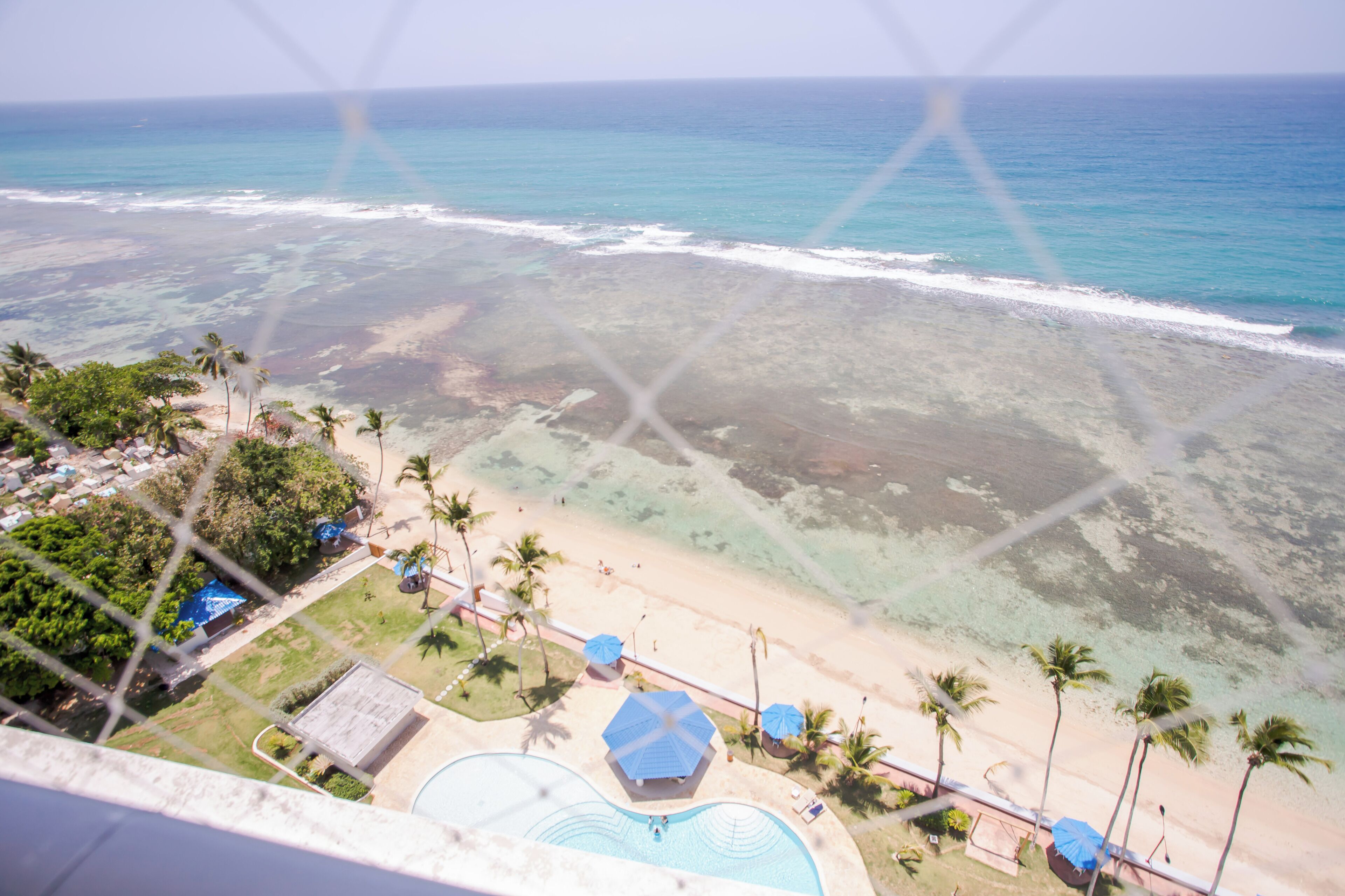 Resort à beira-mar com piscina, guarda-sóis e palmeiras.