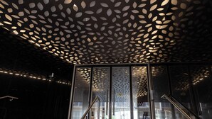 Um interior moderno com teto estampado, escada e entrada de vidro.