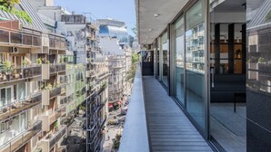 Um edifício alto com uma varanda estreita dando para uma rua movimentada.