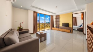A modern living room with a sofa, a coffee table, a TV, and a balcony with a view.