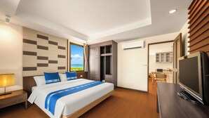 A modern hotel room with a large bed, a desk, a television, and an air conditioning unit.