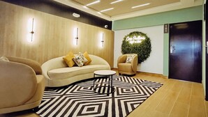 Uma área de espera moderna com um sofá, poltrona e uma mesa pequena.