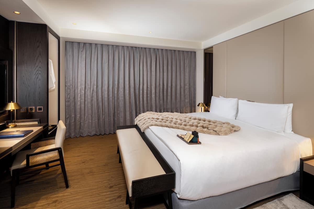Quarto de hotel moderno com uma cama grande, uma escrivaninha e uma cadeira.