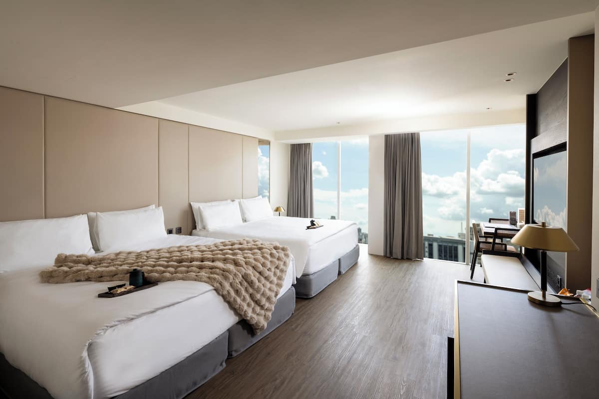 Quarto de hotel moderno com uma cama grande, uma escrivaninha e vista para a cidade.