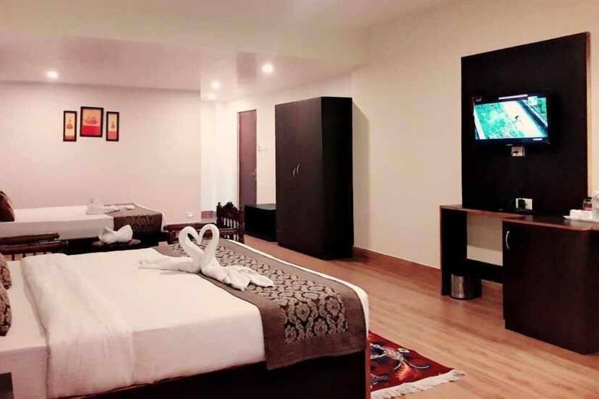 Quarto de hotel com cama, televisão, escrivaninha e guarda-roupa.