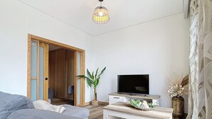 Uma sala de estar moderna com sofá, televisão e plantas decorativas.