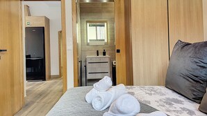 Quarto de hotel com cama, banheiro com espelho e guarda-roupa de madeira.