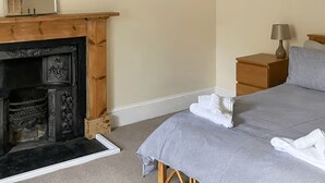 Quarto com lareira, cama com toalhas, mesa de cabeceira e abajur.